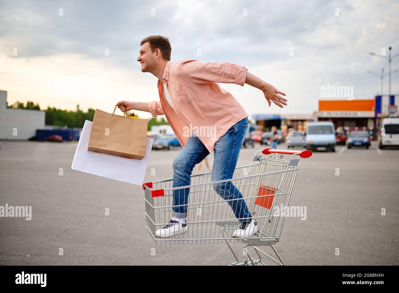 Funny man rides in cart on supermarket car parking Stock Photo - Alamy