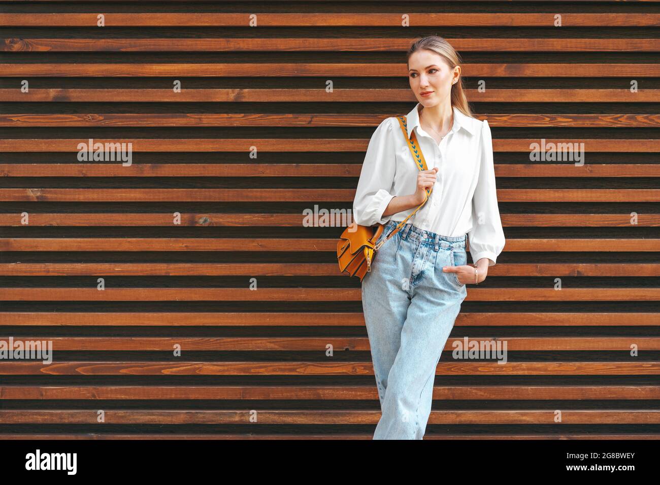 Attractive young stylish woman standing against wooden wall Stock Photo ...