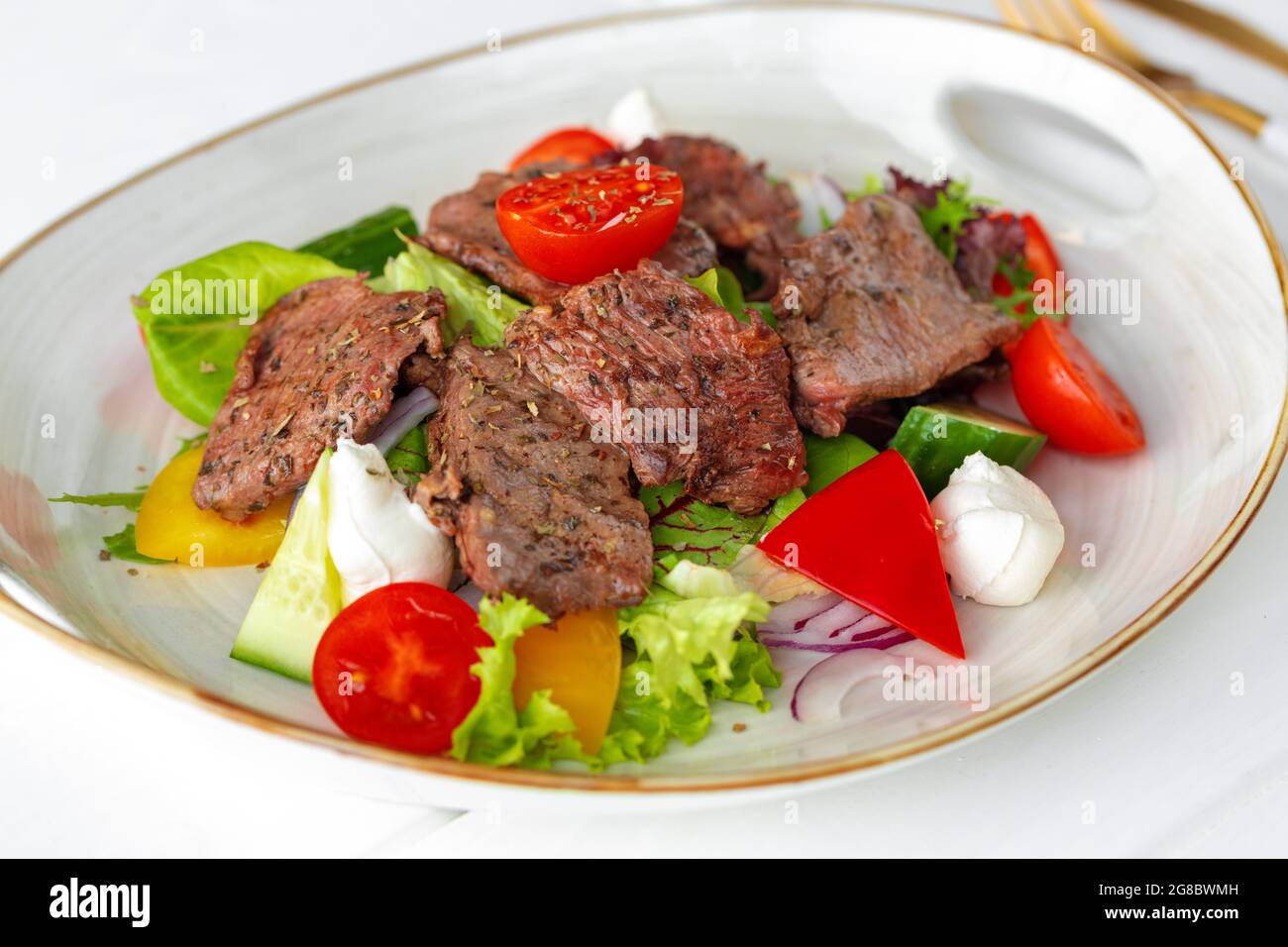 Fillet of beef with vegetable salad on wooden table Stock Photo - Alamy
