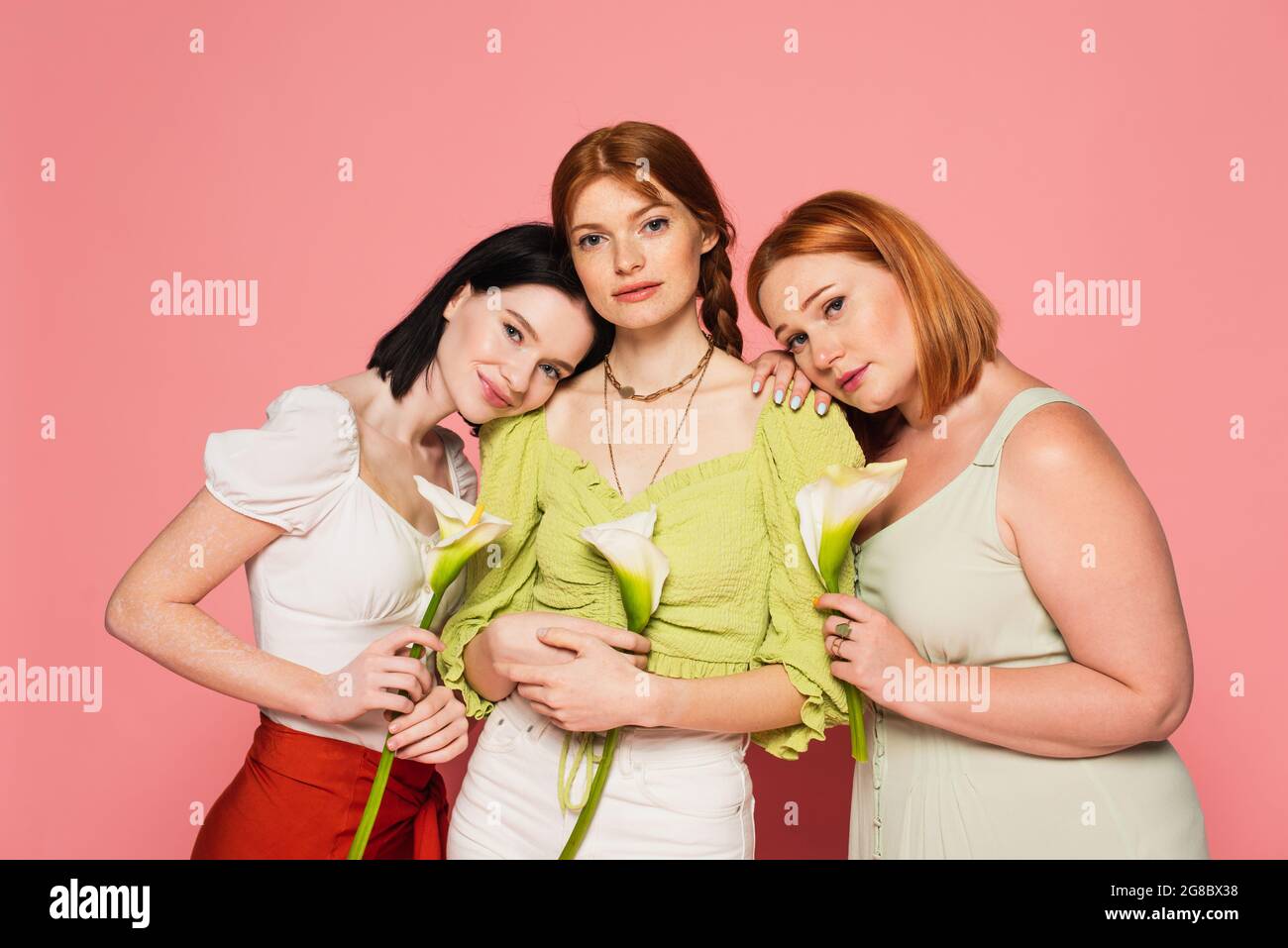 Stylish body positive women holding calla lilies on pink background ...