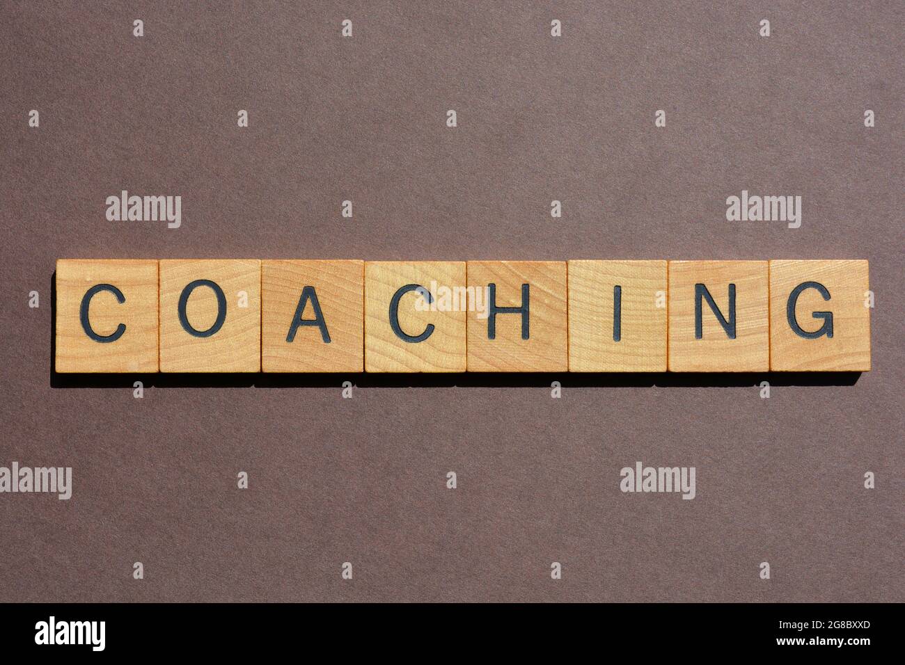 Coaching, word in wooden alphabet letters isolated on brown background ...