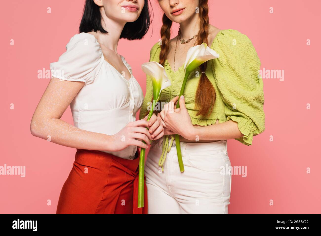 Cropped view of stylish body positive women holding calla lilies ...