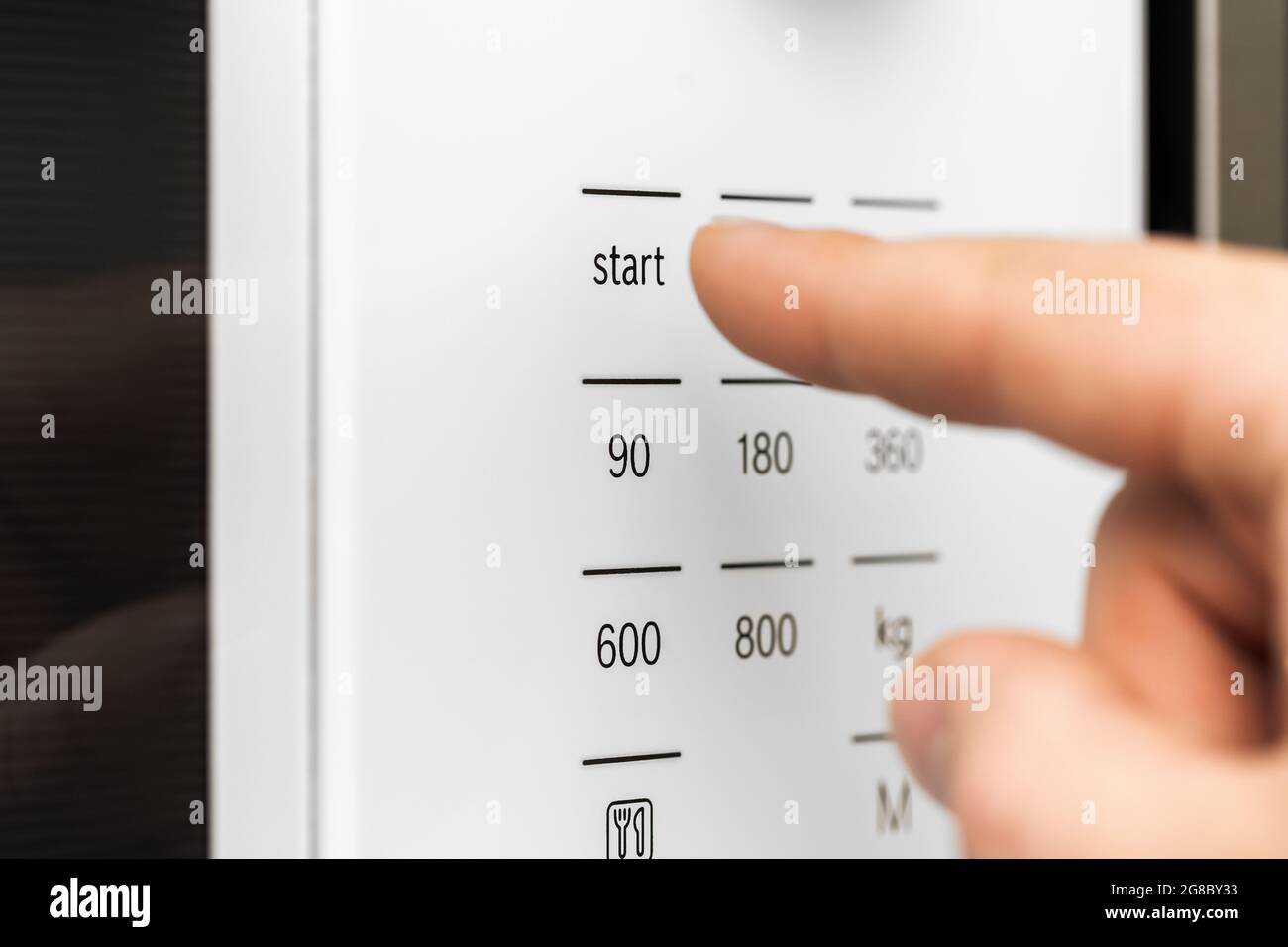 Hand pushing button of microwave oven for cooking food in kitchen Stock ...