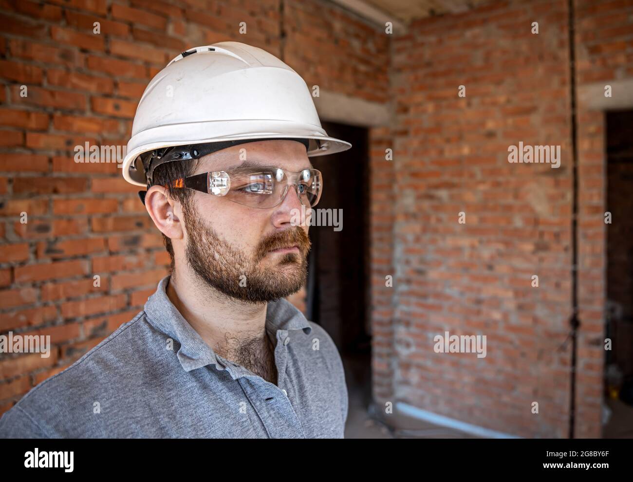 Builder in hard hat and goggles at the work site Stock Photo - Alamy
