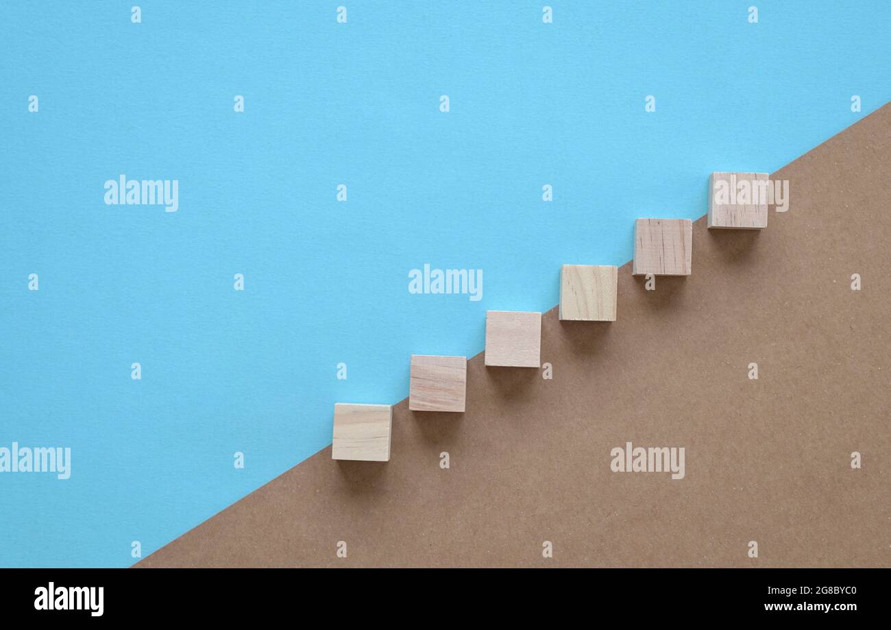 Wood block stacking as step stair. On blue and brown background ...