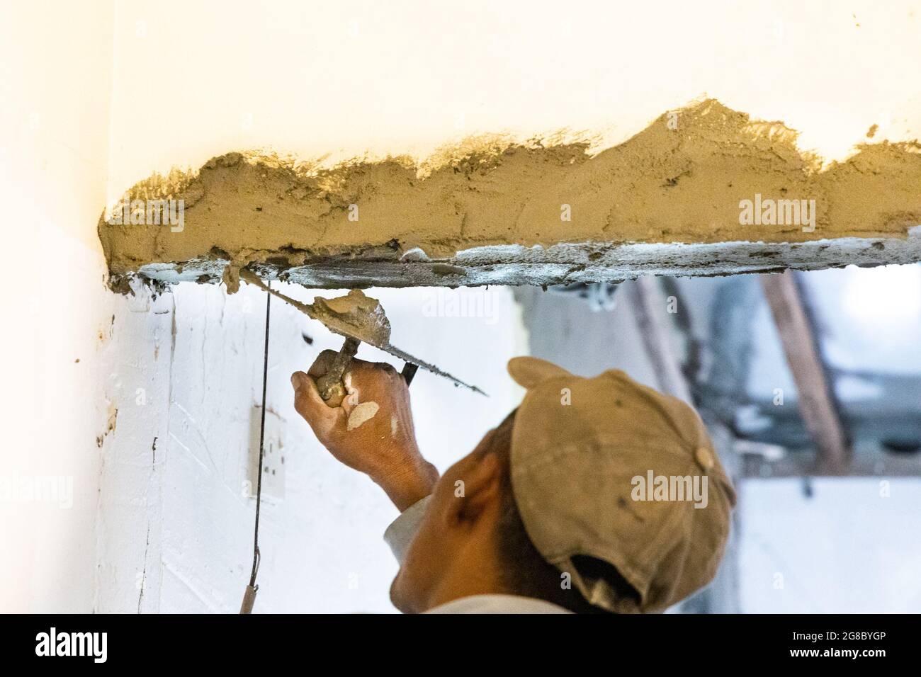 Worker plastering cement mortar on concrete ceiling beam with trowel ...