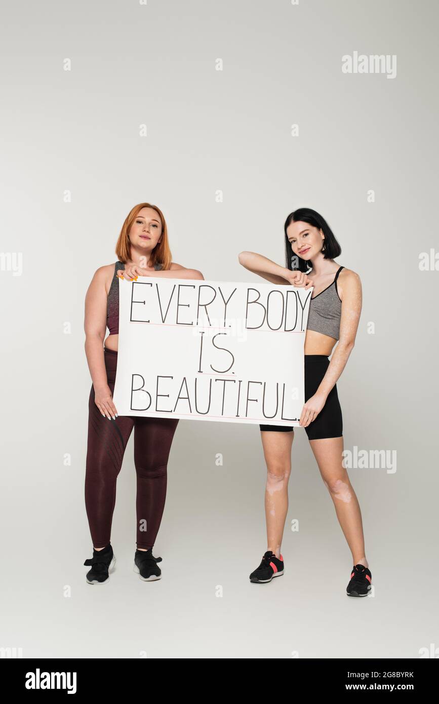 Body positive sportswomen holding placard with every body is beautiful ...