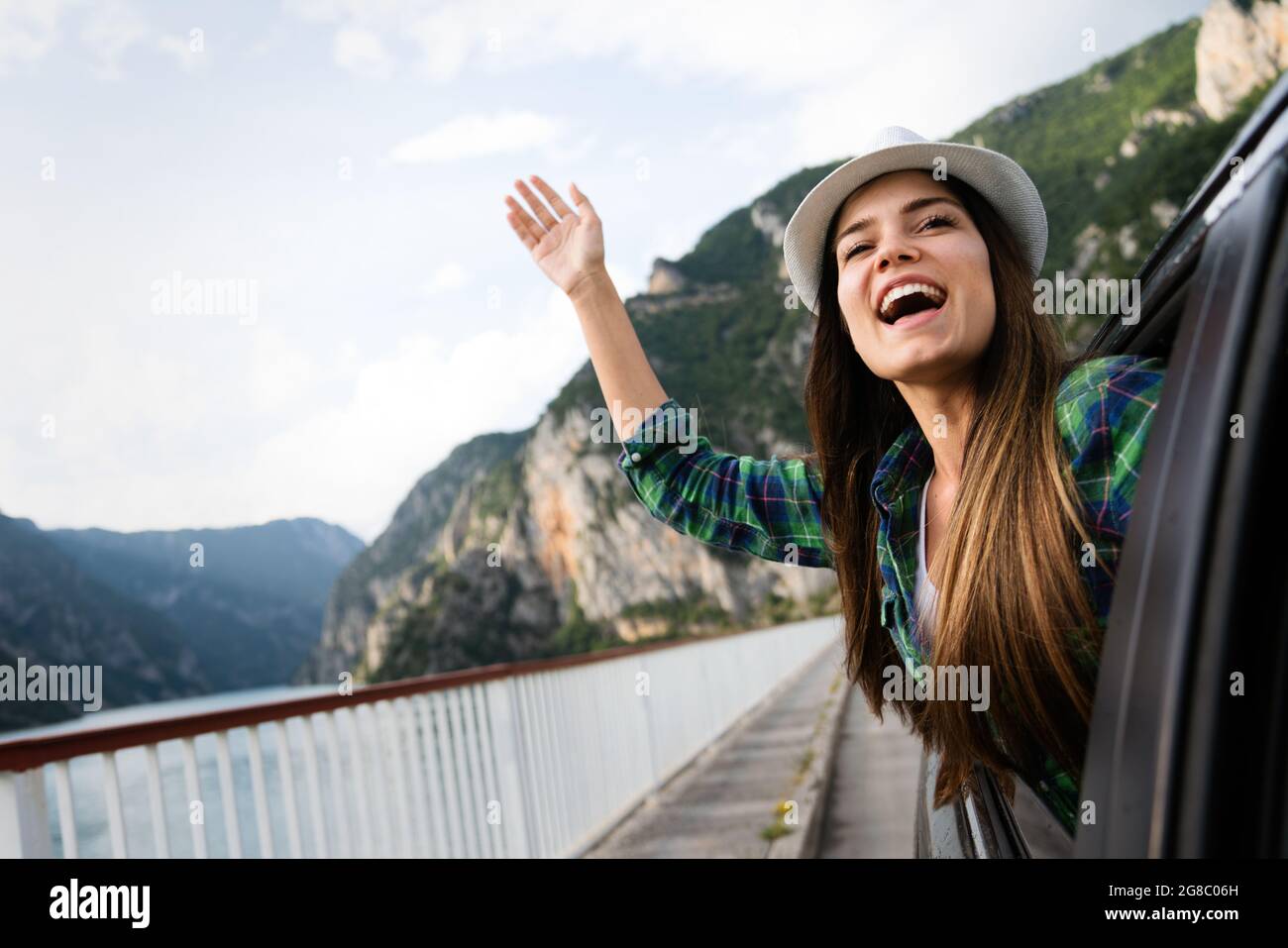 Woman in car road trip waving out the window smiling Stock Photo - Alamy