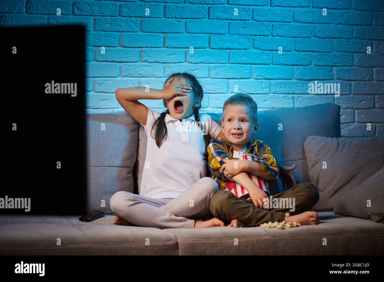 two children with remote control watching TV Stock Photo - Alamy