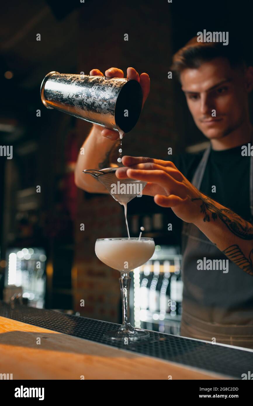 Preparing cocktail for woman. One professional bartender pouring ...