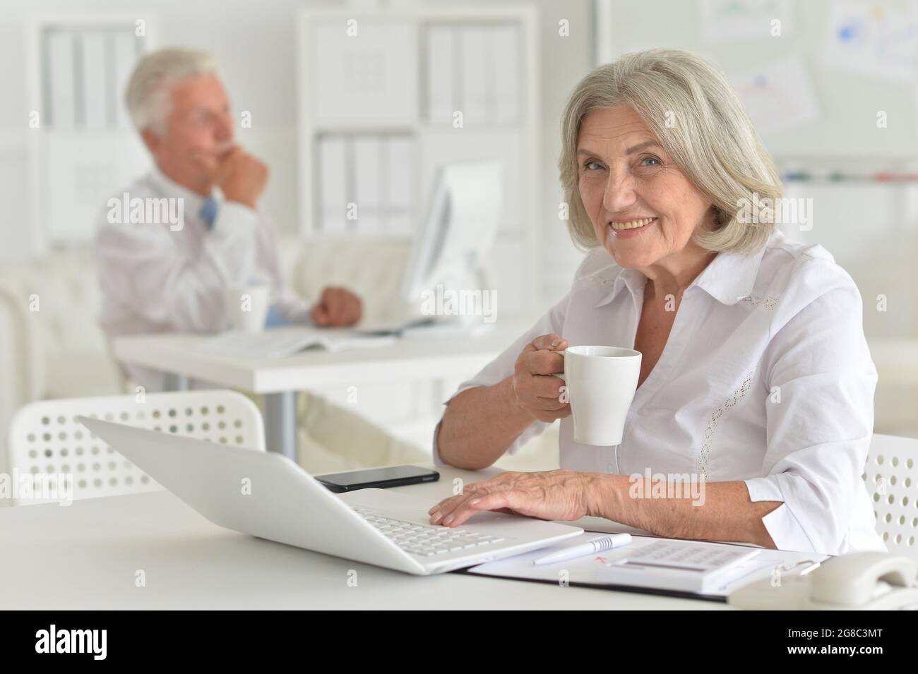 Senior woman working in office with laptop Stock Photo - Alamy