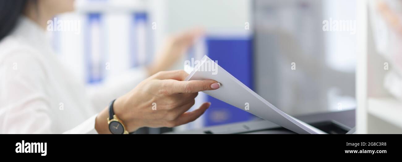 Young woman pulling paper out of printer closeup Stock Photo - Alamy