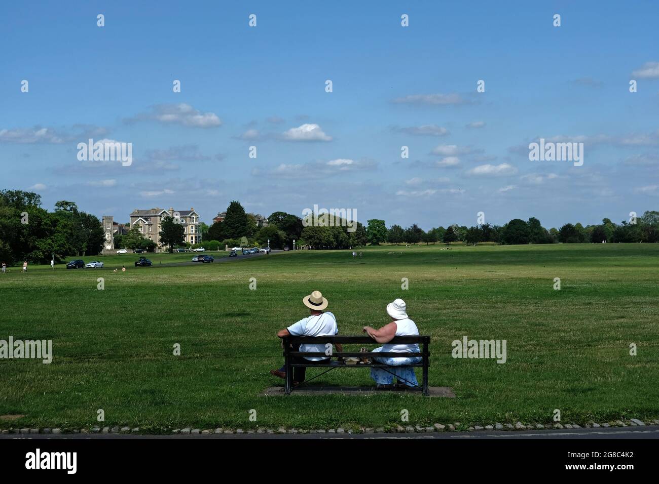 Two older people sitting in the sunshine on Bristol Downs wearing sun ...