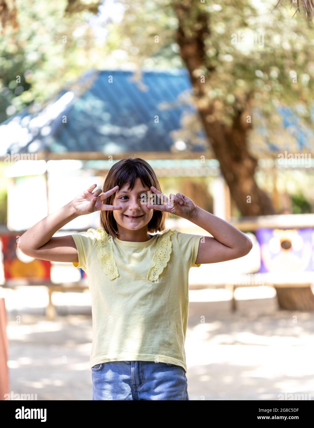 Vertical shot of a young short-haired girl with a yellow shirt and blue ...