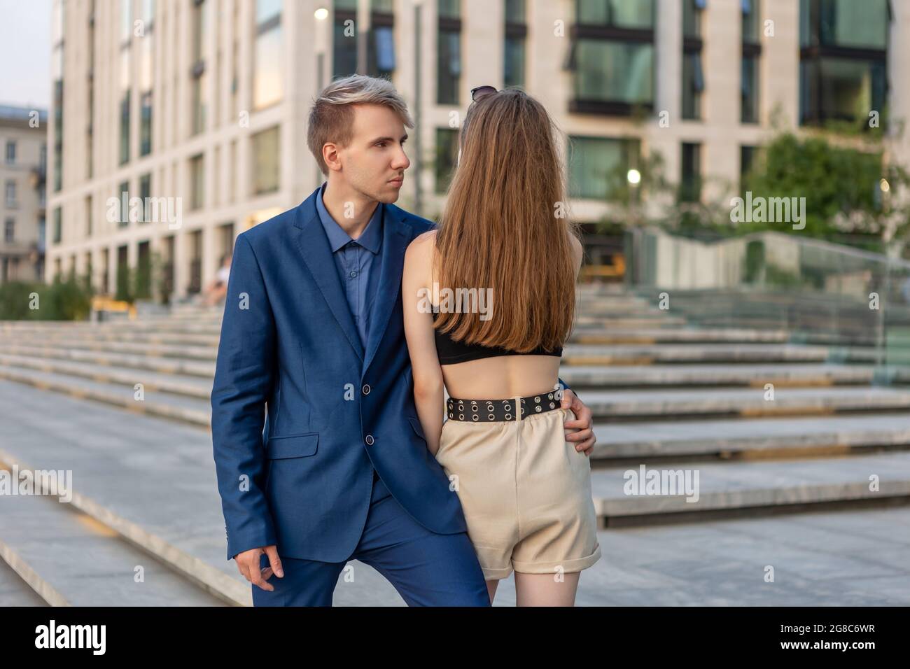 Guy in business suit hugs girl in shorts on street Stock Photo - Alamy