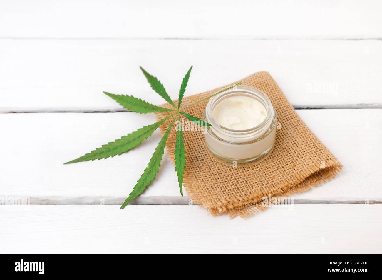 Cannabis infused cream bottle on white wooden background with marijuana ...
