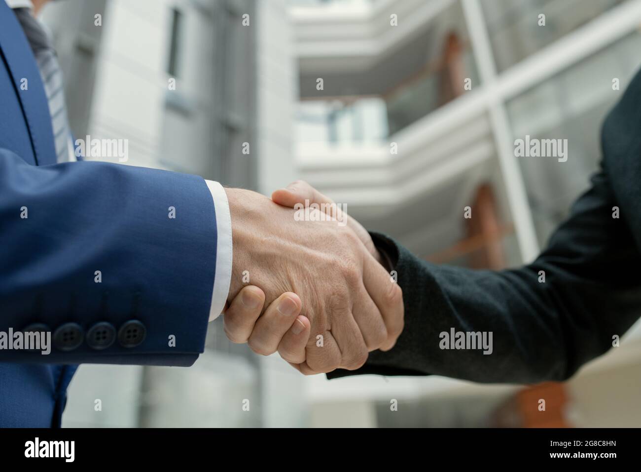 Close-up of two architects shaking hands against the office building ...