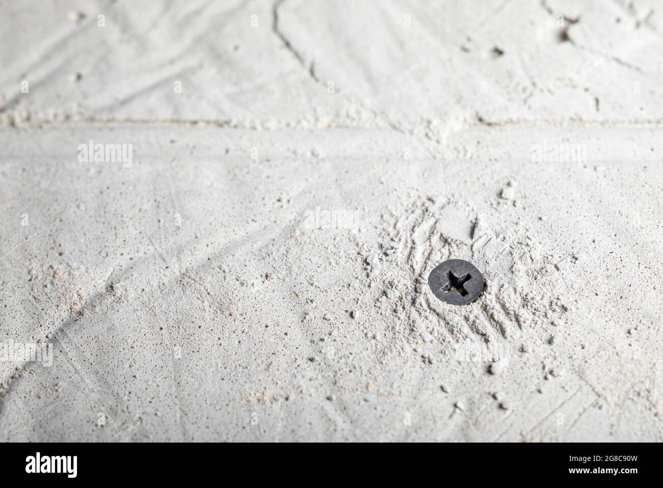 Black self-tapping screw screwed into a dowel installed in concrete ...