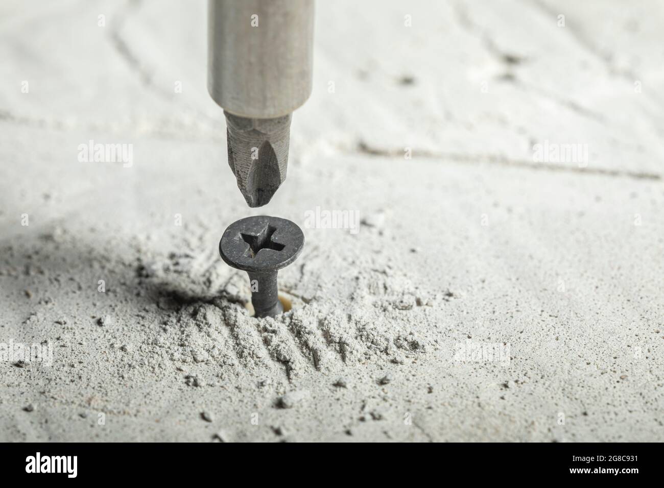 Black self-tapping screw screwed into a dowel installed in concrete ...