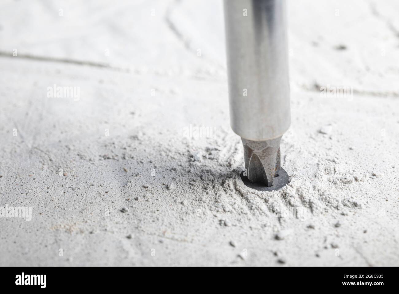 Black self-tapping screw screwed into a dowel installed in concrete ...