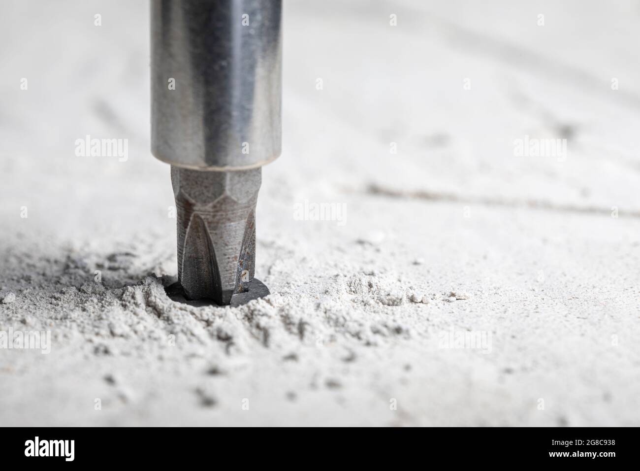 Black self-tapping screw screwed into a dowel installed in concrete ...
