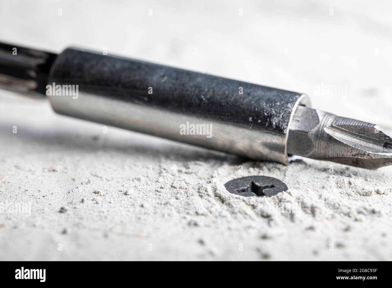 Black self-tapping screw screwed into a dowel installed in concrete ...
