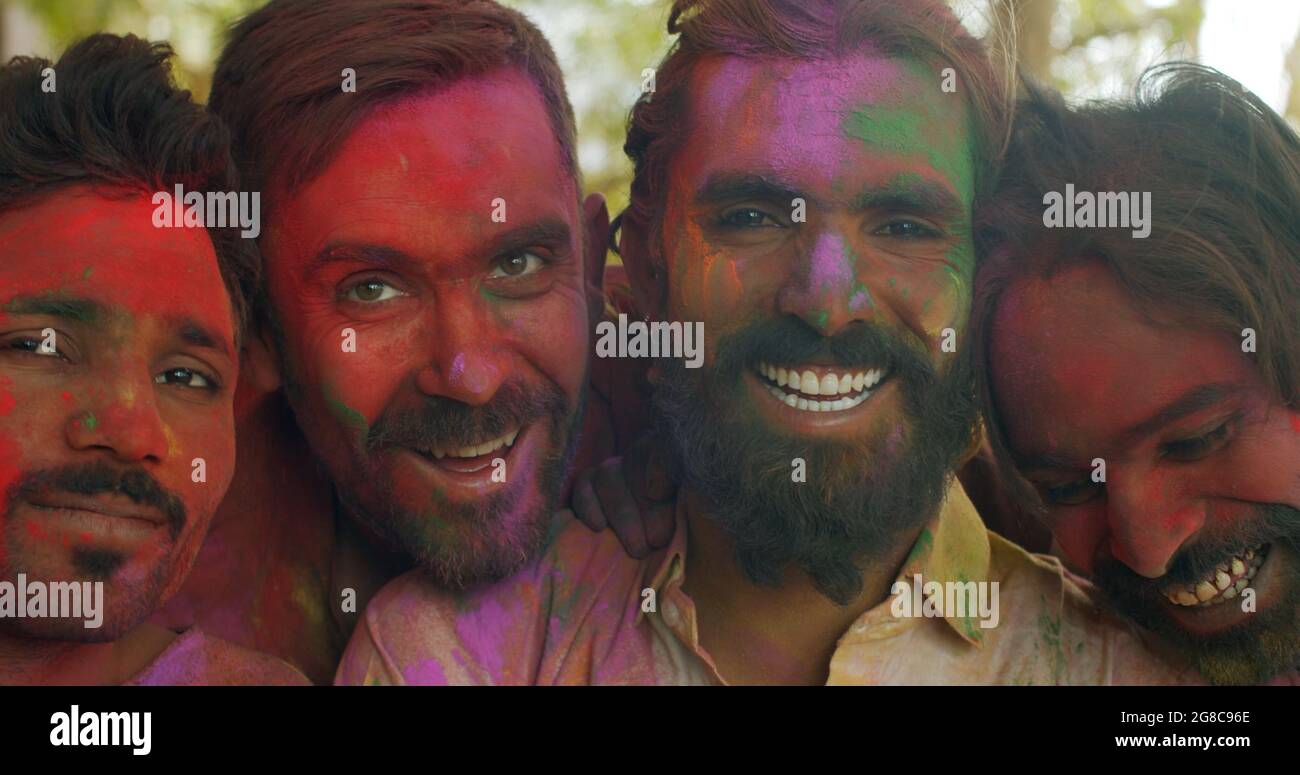 Portrait of four guys with colorful paint on their faces celebrating ...
