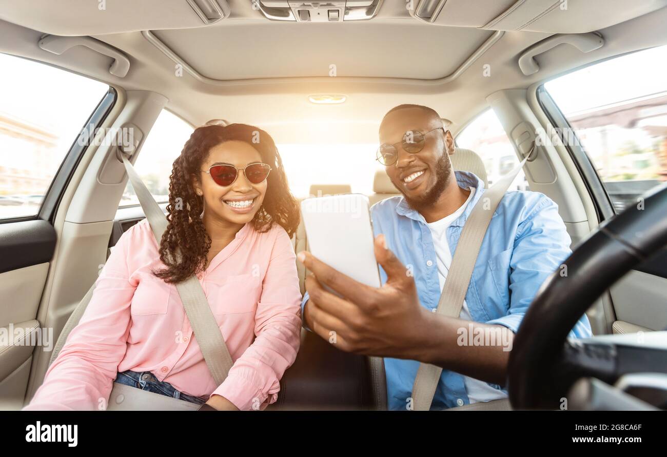 Happy black man and woman driving car and using smartphone Stock Photo ...