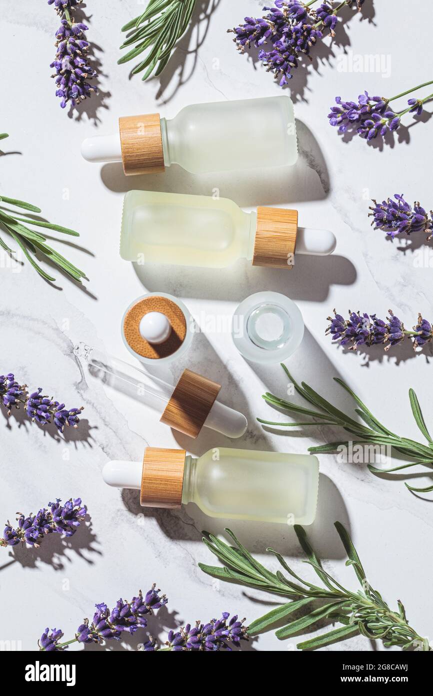 Flat lay of lavender essential oil in glass bottles, white marble ...