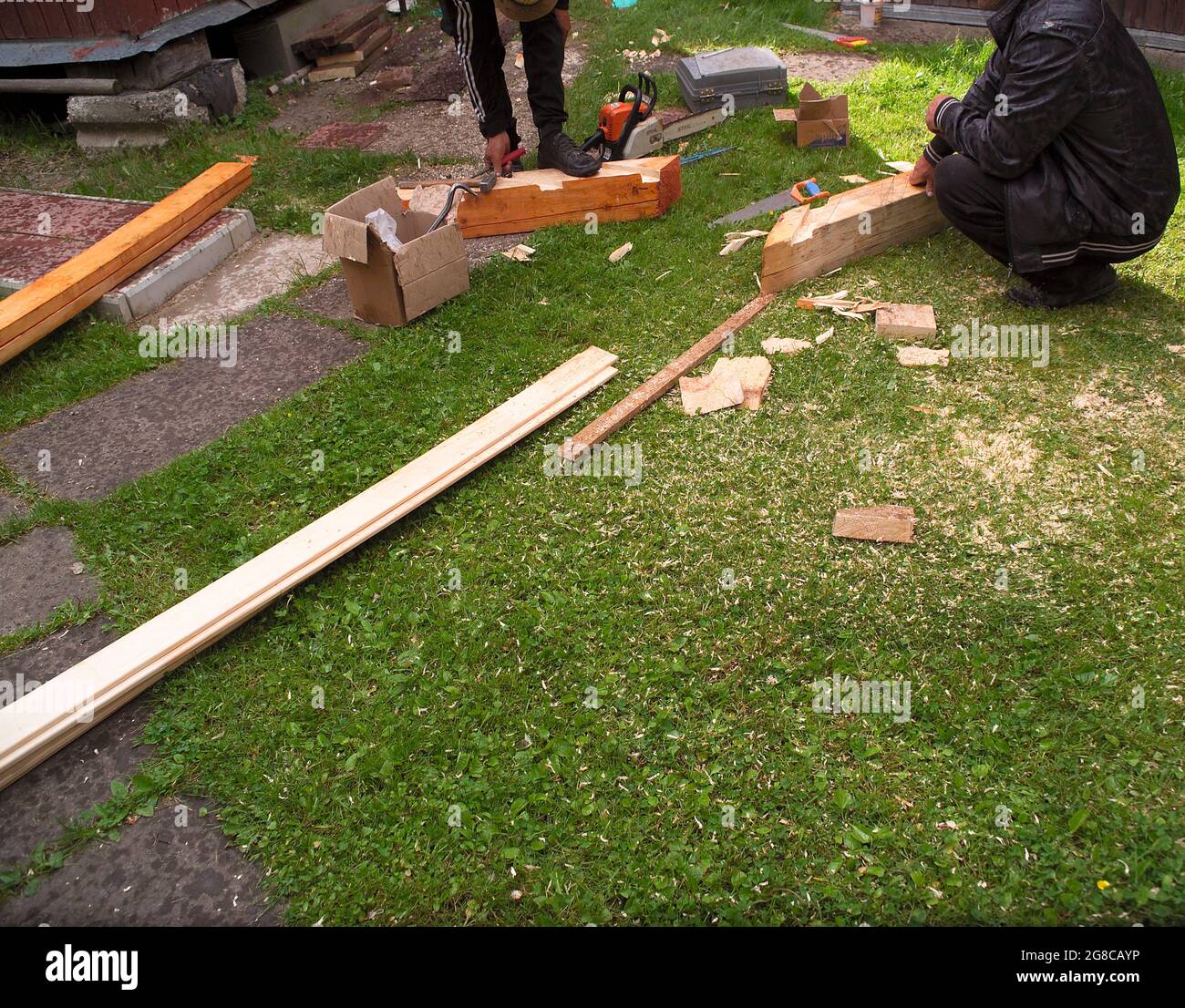 two carpenters working in a messy yard, outdoor shot with no ...