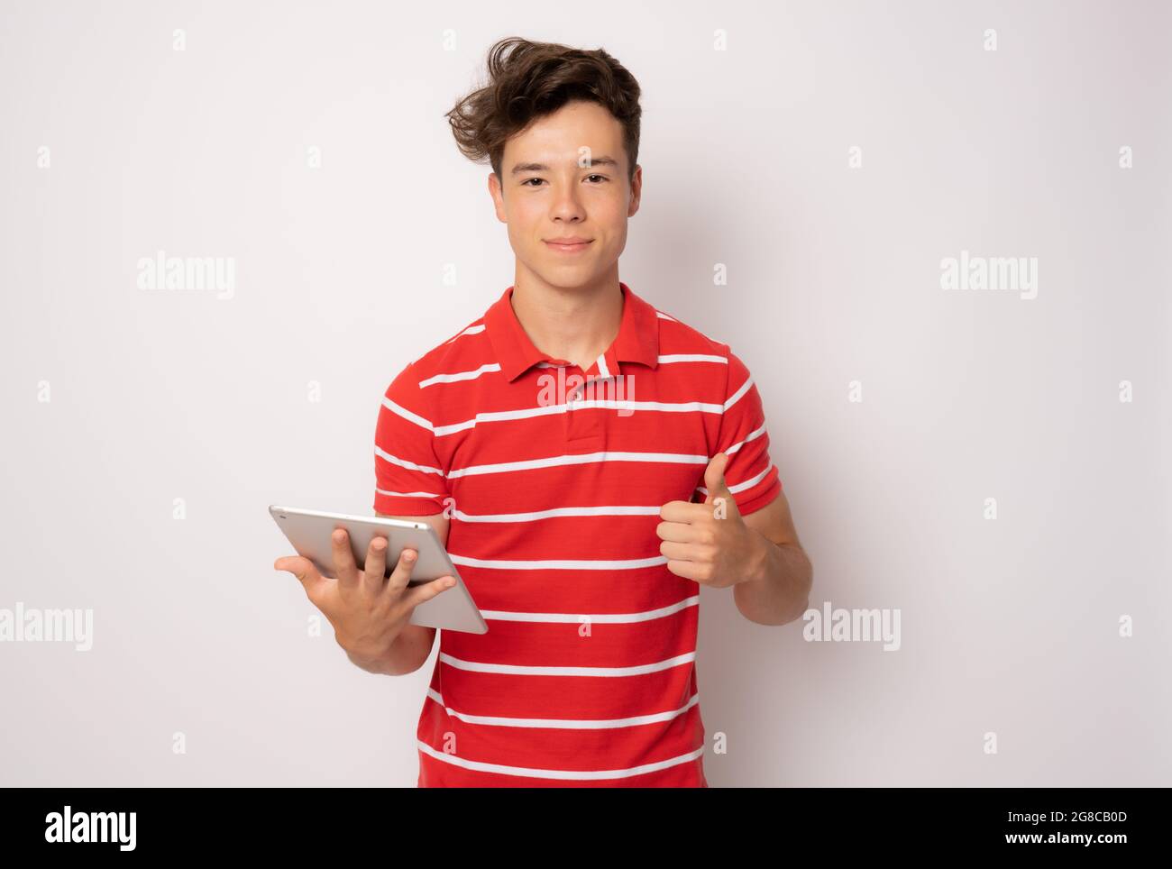 Young man in casual clothes holding tablet with thumb up isolated over ...