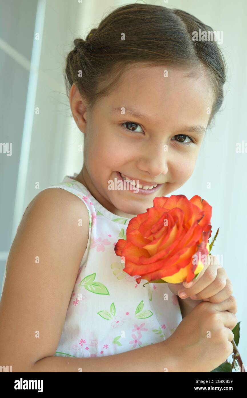 Portrait of a cute little girl at home with rose Stock Photo - Alamy