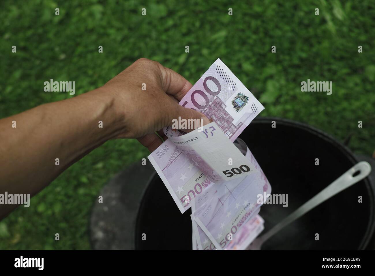 a hand throwing european currency into a food bowl Stock Photo - Alamy
