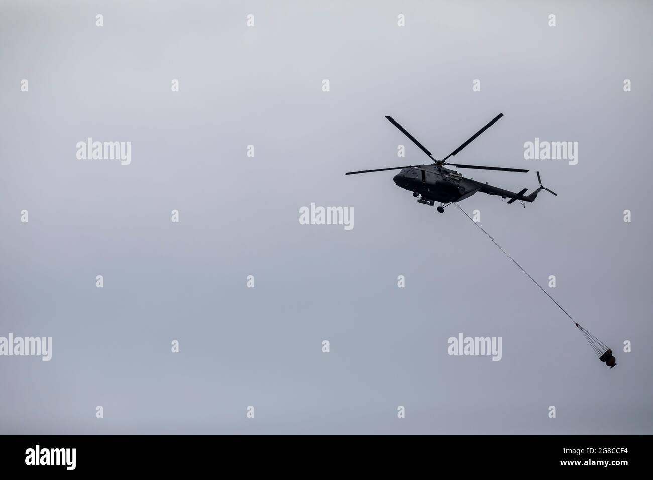 Firefighter helicopter with a water tank on the background of the sky ...