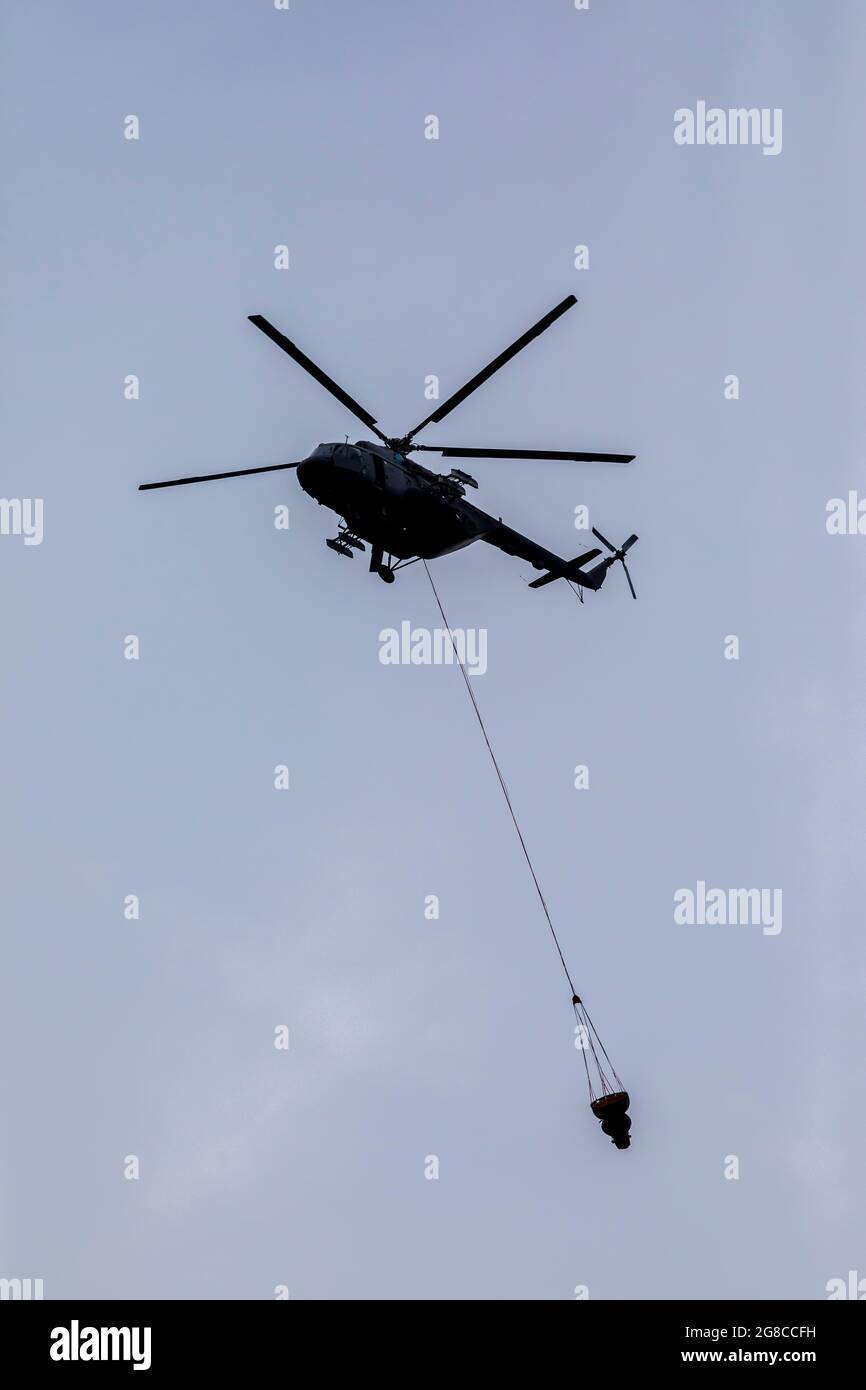Firefighter helicopter with a water tank on the background of the sky ...