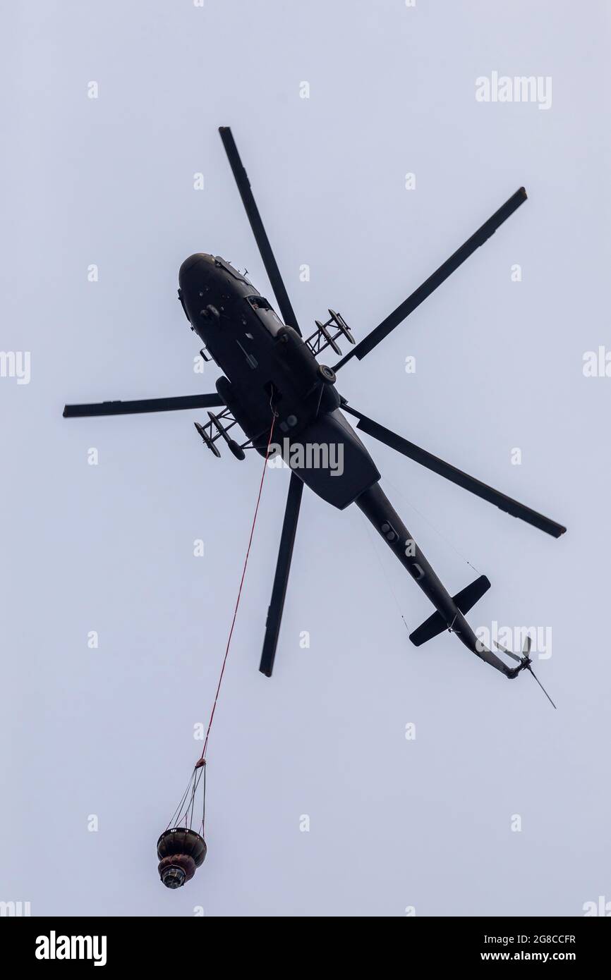 Firefighter helicopter with a water tank on the background of the sky ...