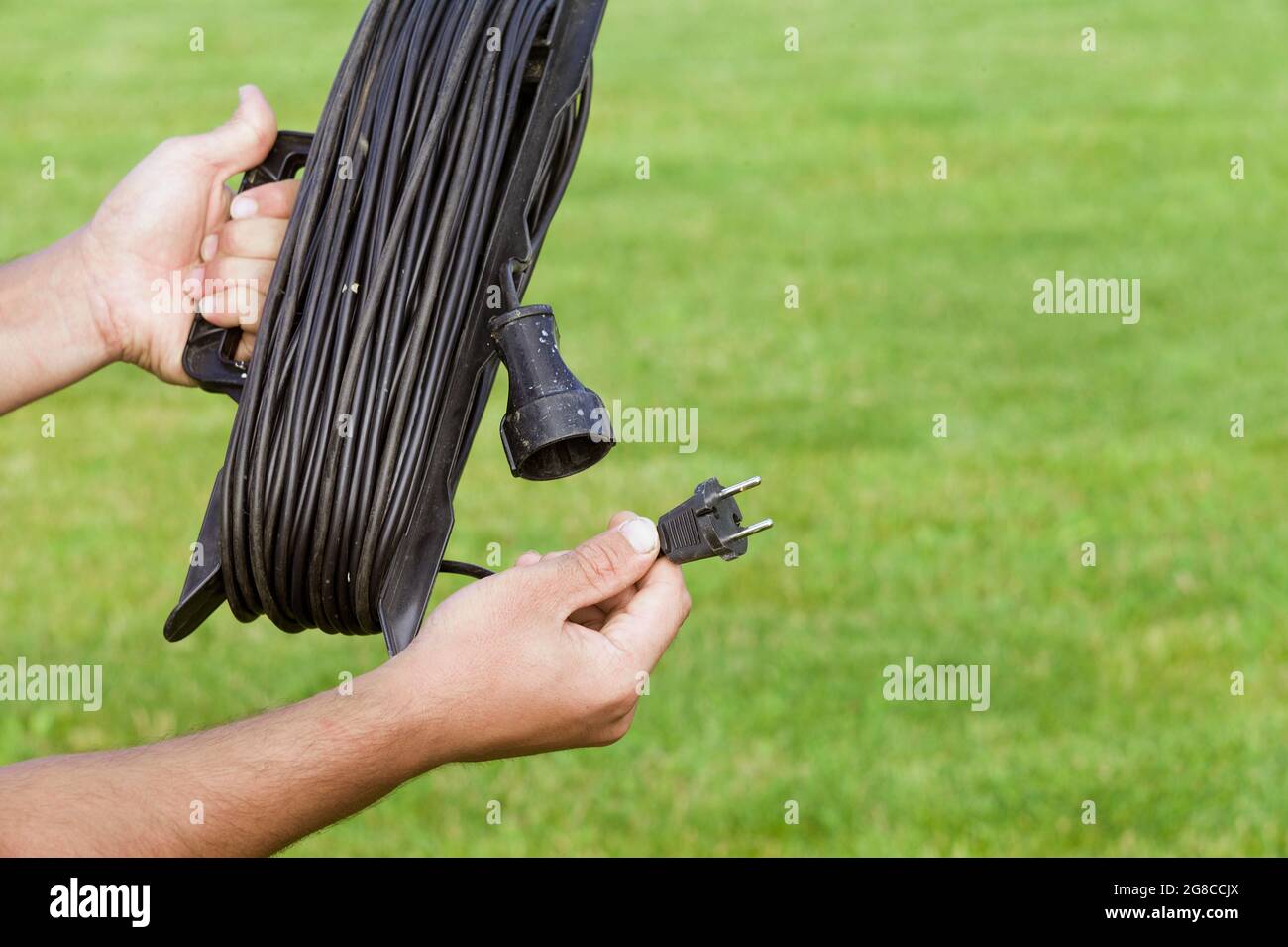 Roll of extension electric cable in a male hand, outdoor close up Stock ...