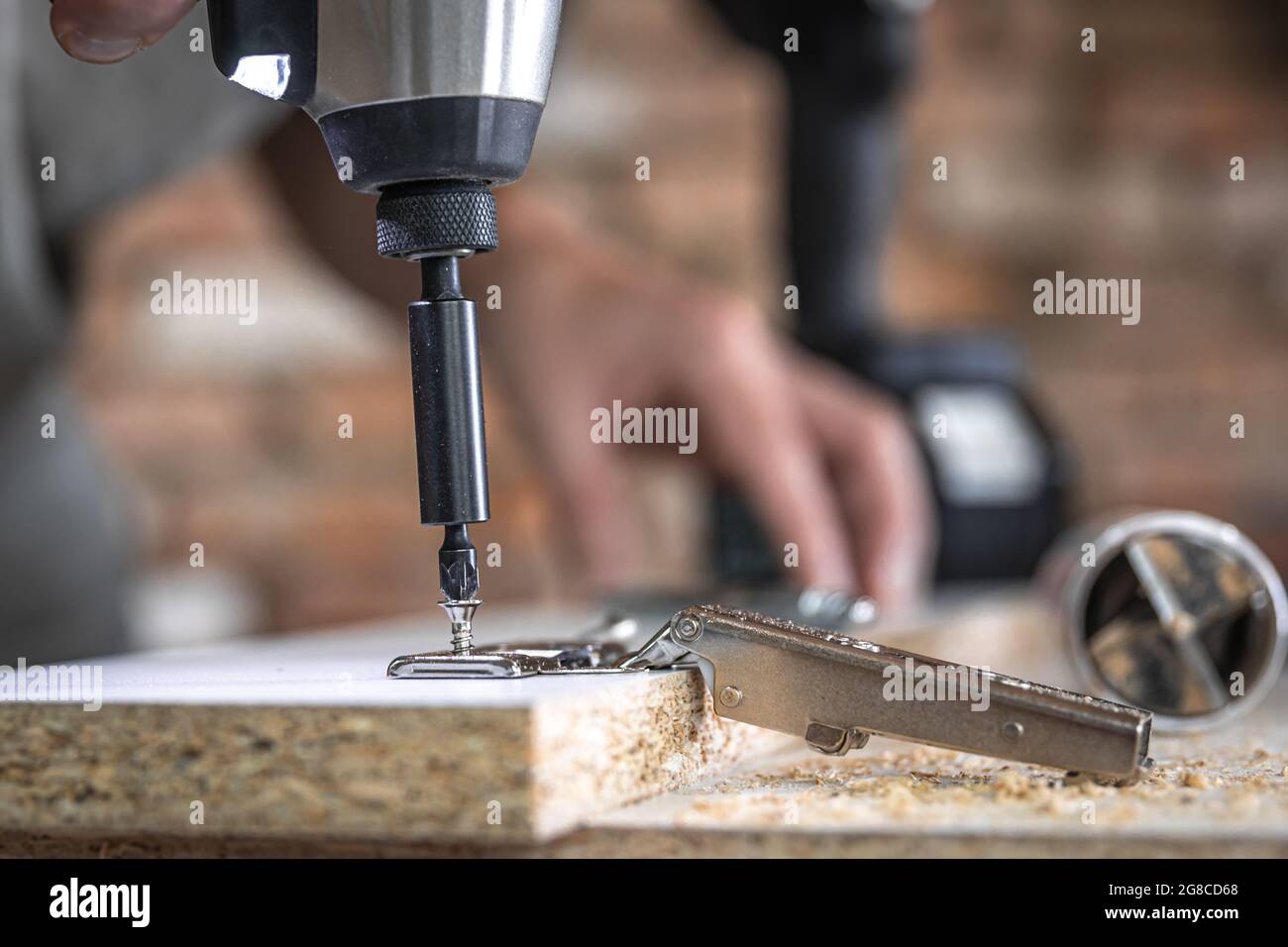 Screwing a self-tapping screw into a metal fastening hole on a wood ...