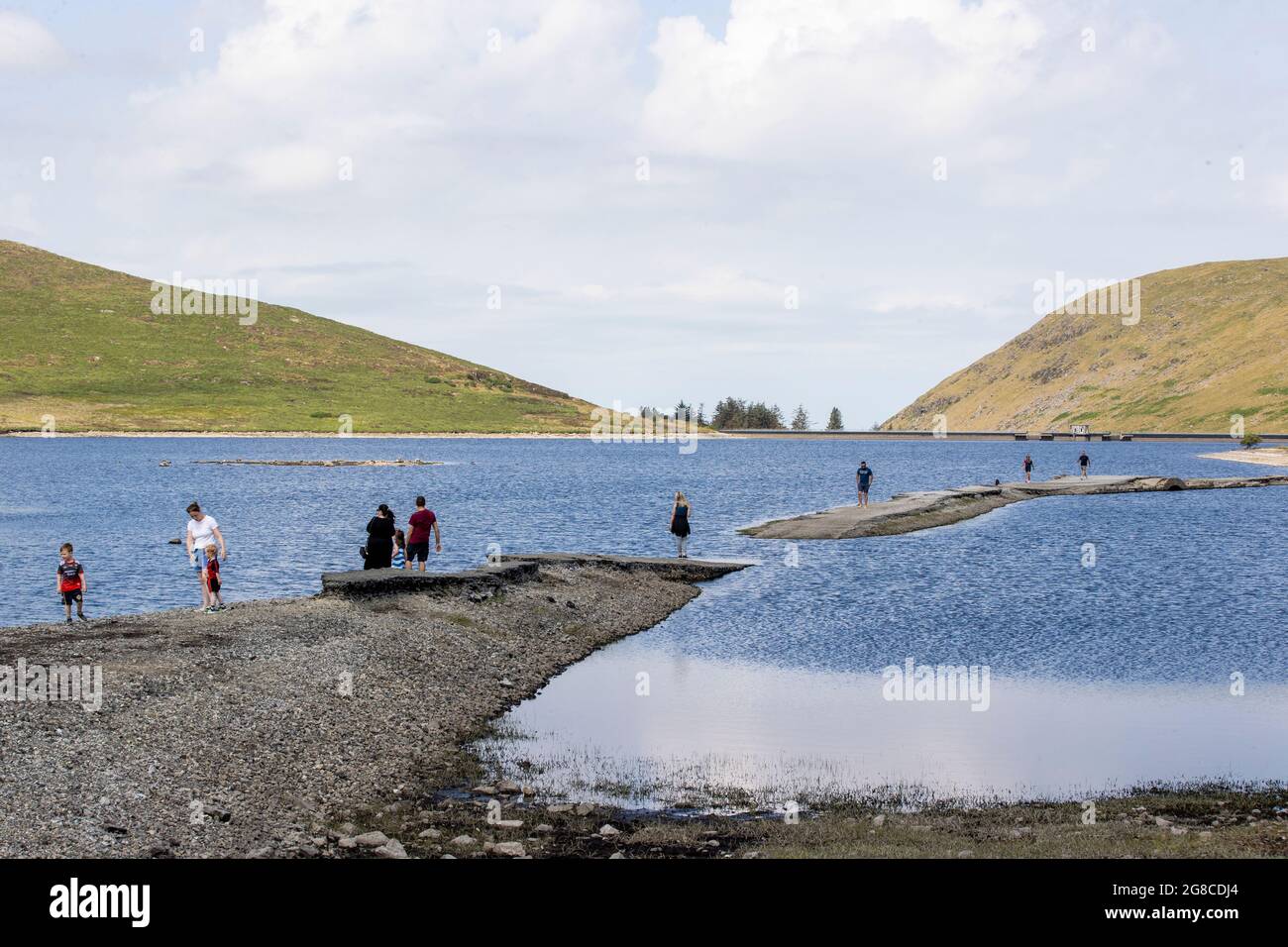 People walk along a pathway exposed by the falling water level at ...