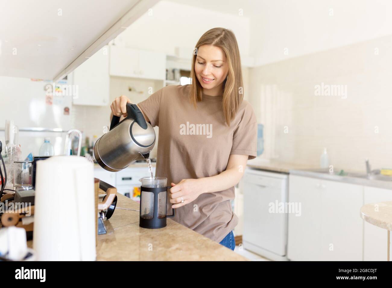 Happy young woman making coffee in kitchen - french press coffee ...