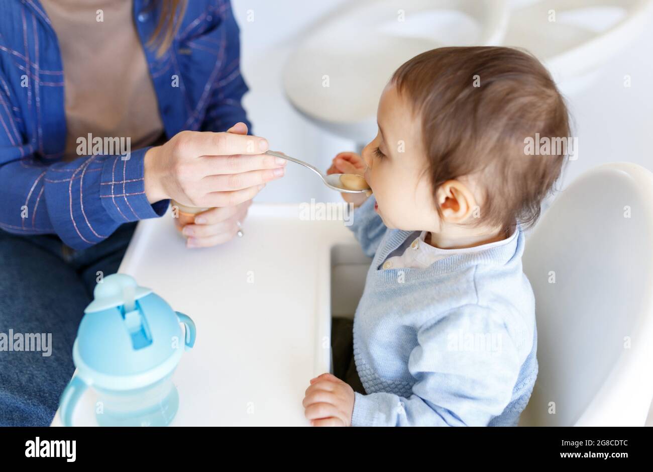 cropped mother feed little toddler baby boy with baby food, from ...
