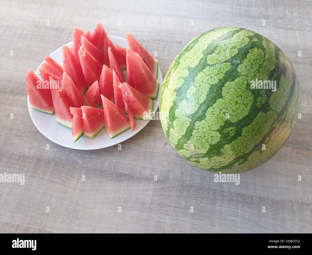 A portrait of an uncut green, big and round watermelon next to a white ...