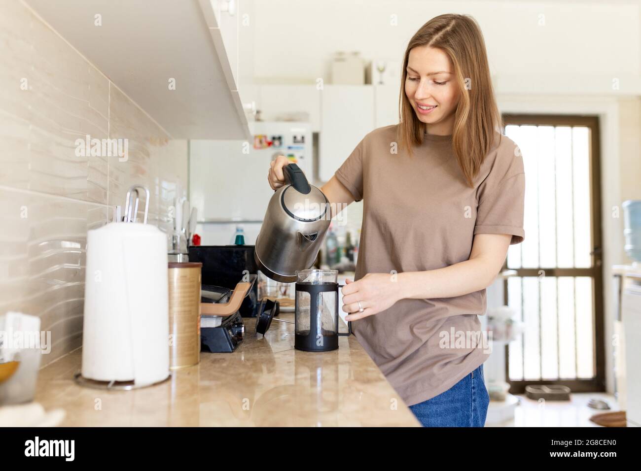 Happy young woman making coffee in kitchen - french press coffee ...