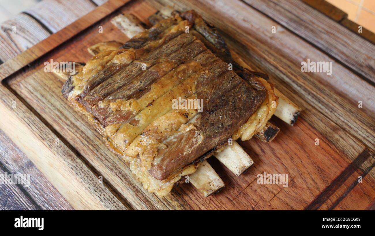 Costela. Delicious roast rib with big bones. Served on a wooden board Stock Photo - Alamy