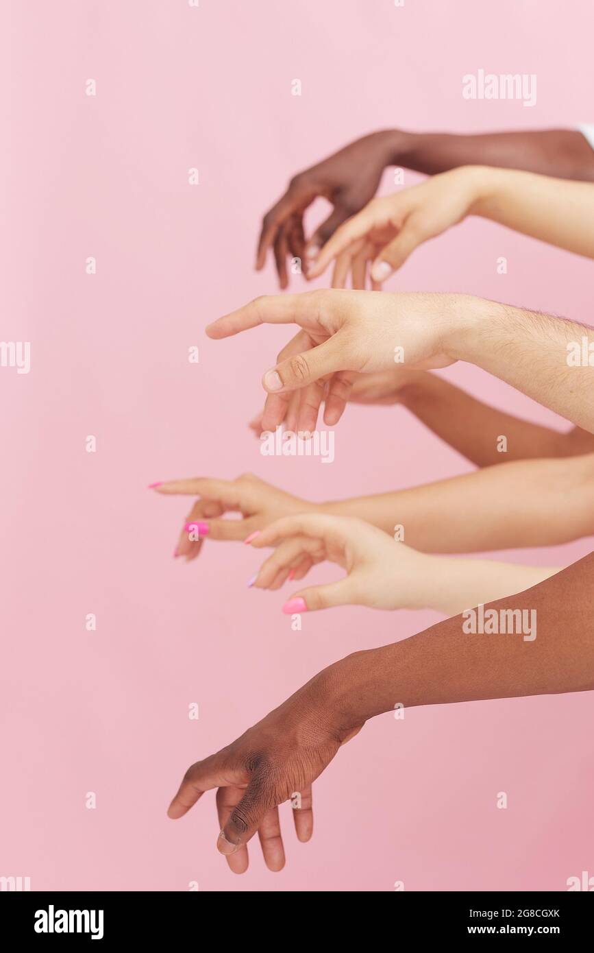 Art. African American and Caucasian hands showing on pink studio ...