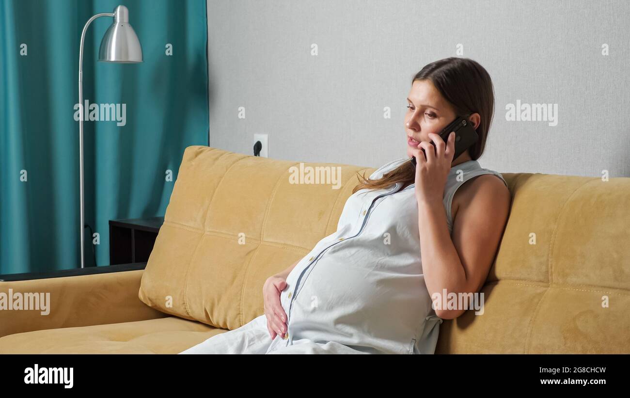 Pregnant woman talking on the phone experiencing contractions while ...
