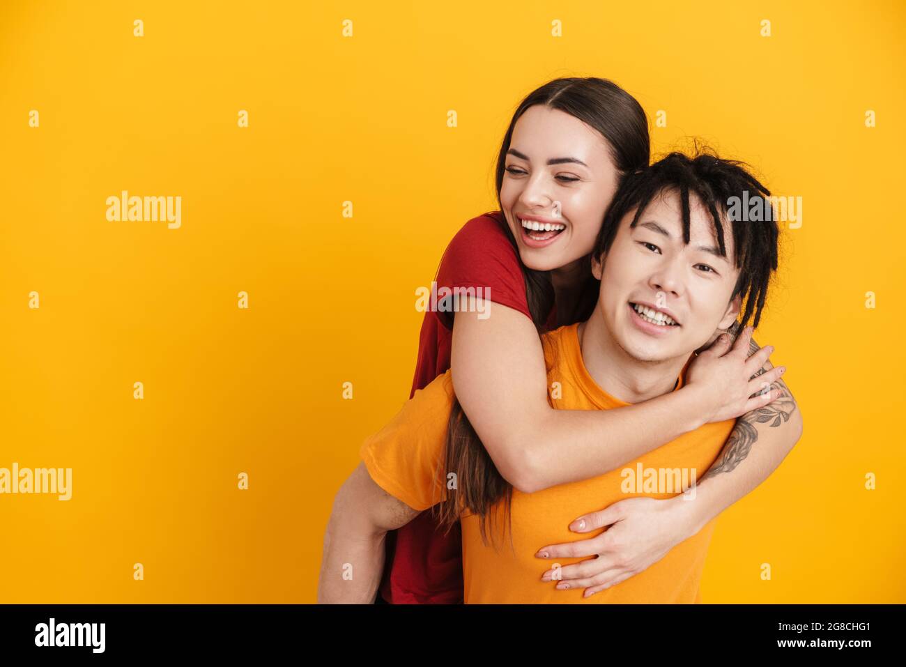 Young multiracial couple laughing while doing piggyback ride isolated ...
