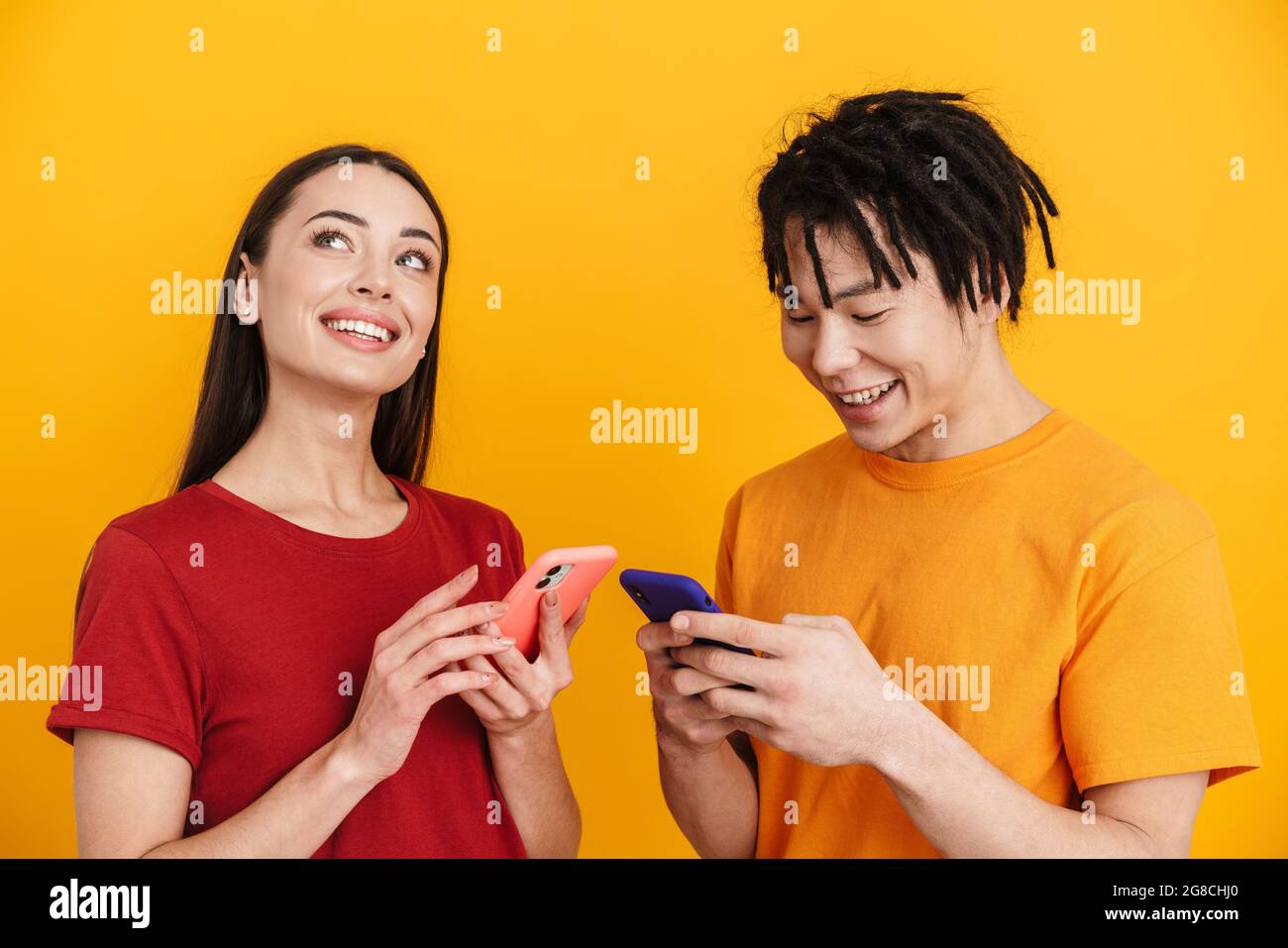 Young multiracial couple smiling and using mobile phones isolated over ...