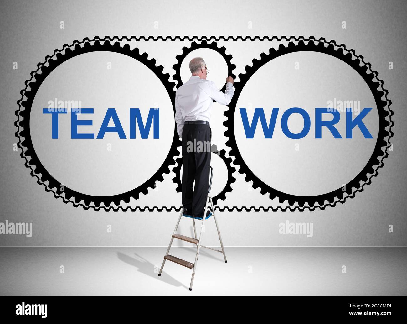 Man on a ladder drawing teamwork concept on a wall Stock Photo - Alamy