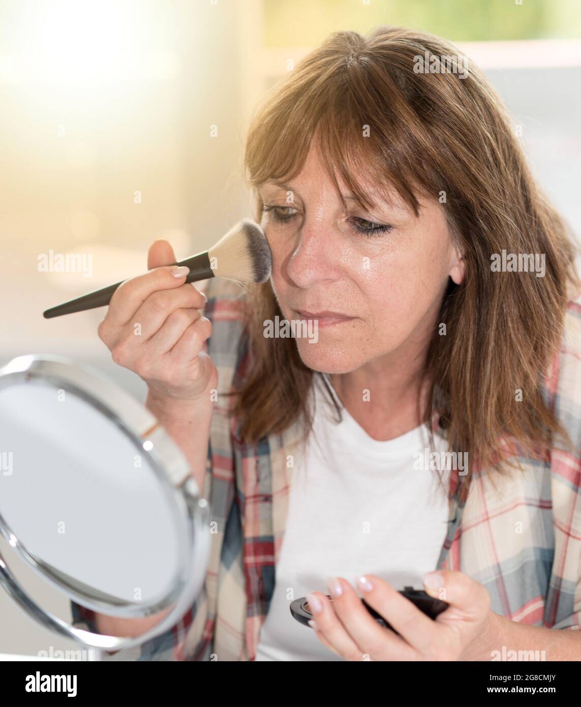Mature woman applying cosmetic powder on her face Stock Photo - Alamy